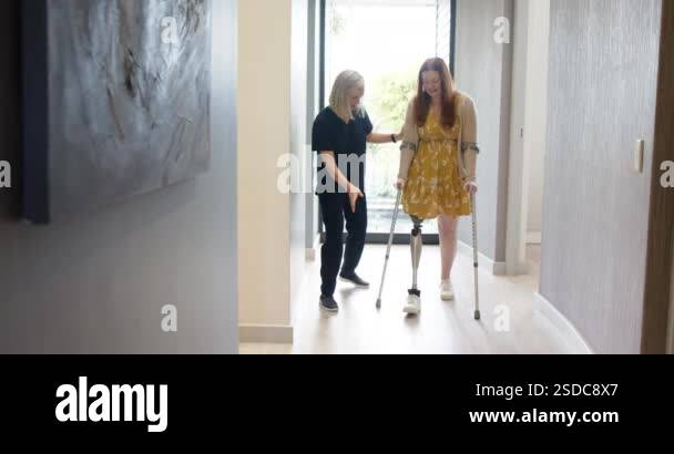Woman with prosthetic leg walking using crutches with therapist in ...
