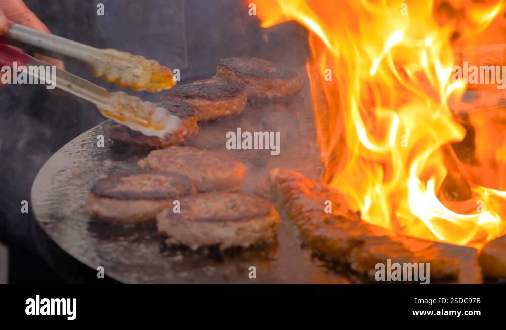Slow motion: chef grilling meat cutlets for burgers on brazier with hot ...