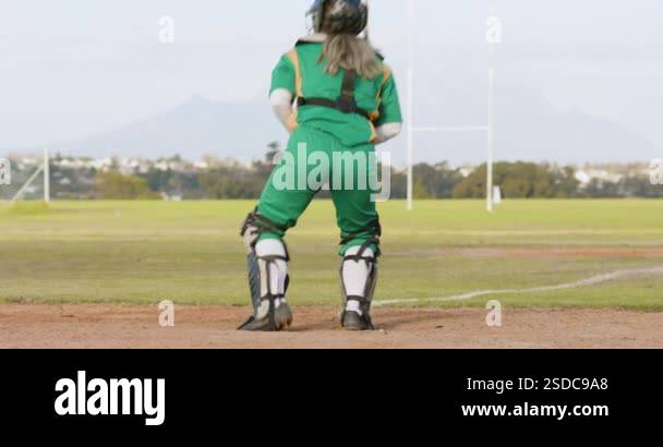Female baseball player wearing green uniform, catching and throwing the ...