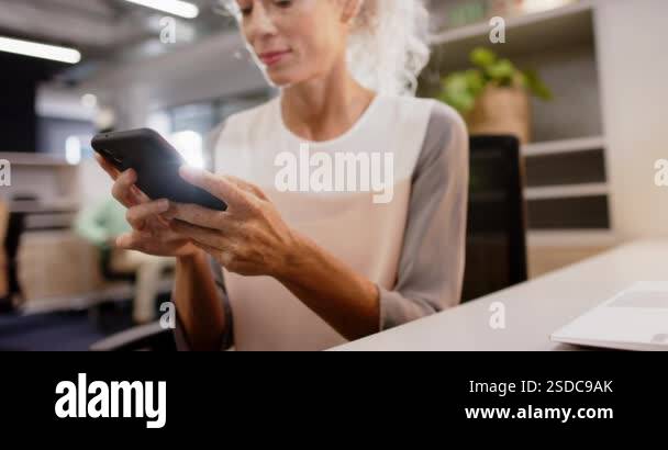 Using smartphone, woman texting and working in modern office ...