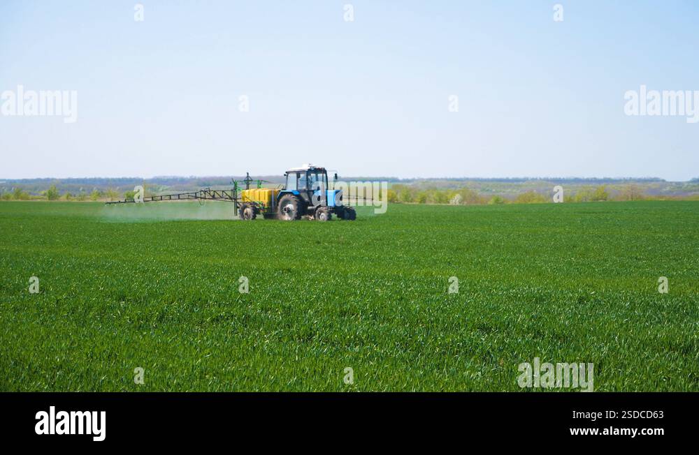 Farming tractor spraying on field with sprayer, herbicides and ...