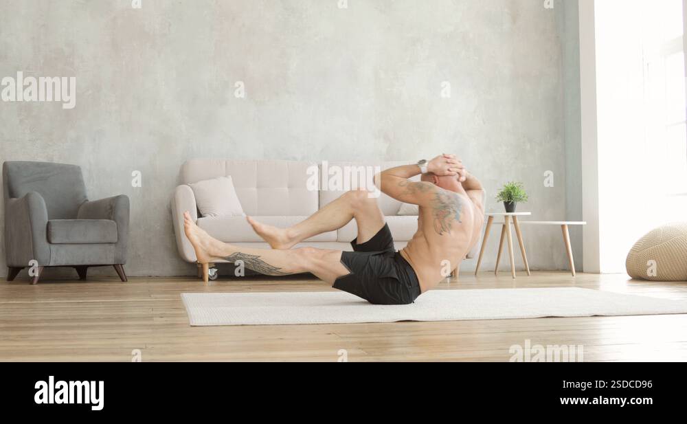 Sporty muscular man is doing abs exercises crunches at home on floor ...