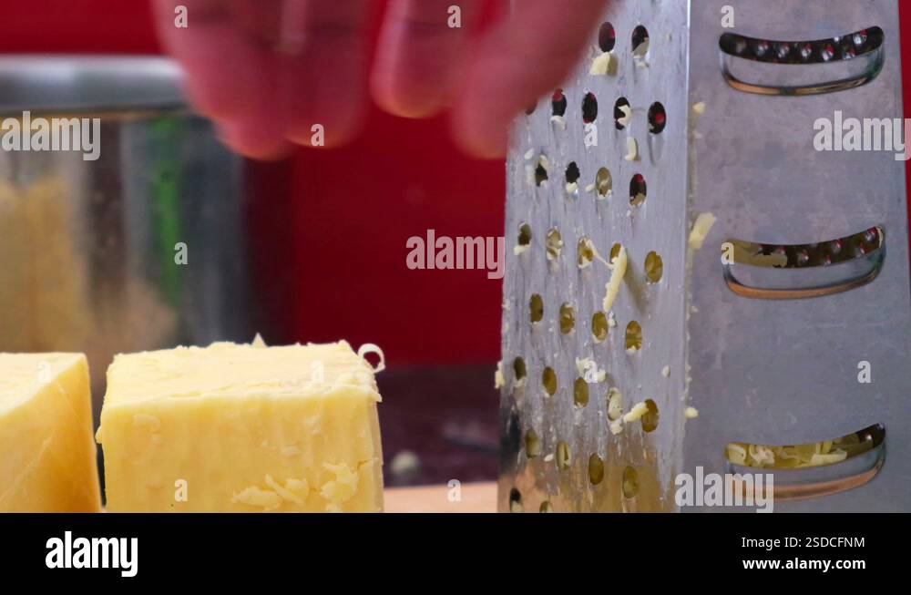 extreme close up shot of shredding cheese, a hand picking up a block of ...