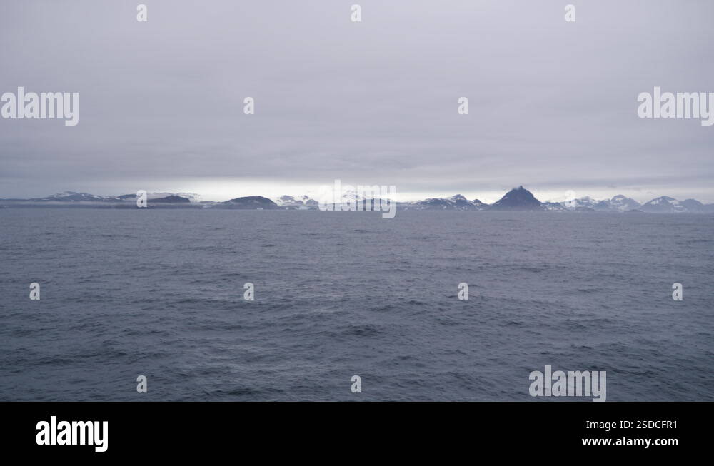 Distant snow capped mountains on a frozen horizon with dark moody ...