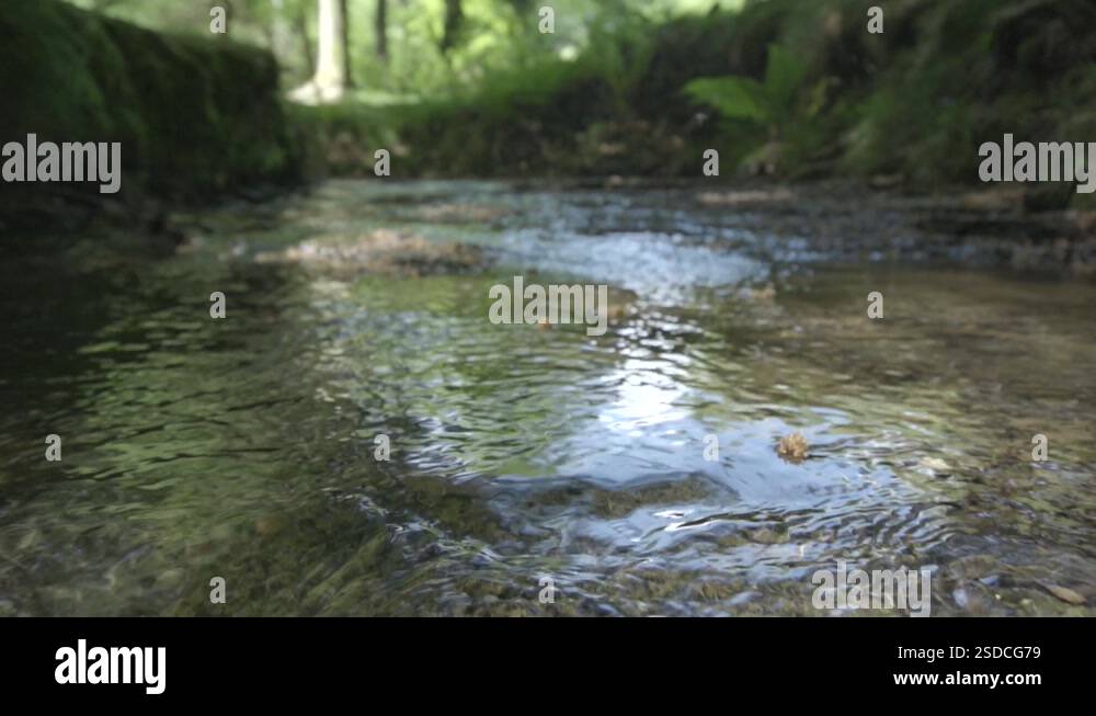 Stream of water cascades gently down rocks in river, low close up ...