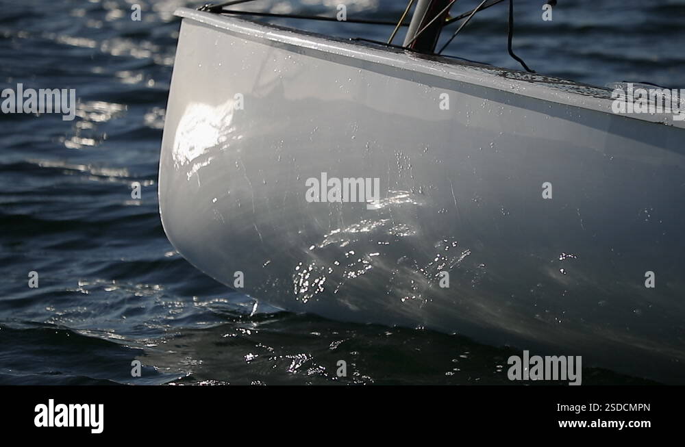 White Sail boat stern on water in slow motion with flickering light on ...