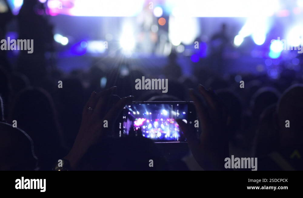 Recording with a mobile phone a concert show live between the crowd ...