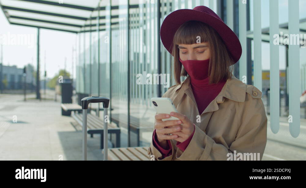 Woman in cotton prottective mask using mobile phone while sitting on ...
