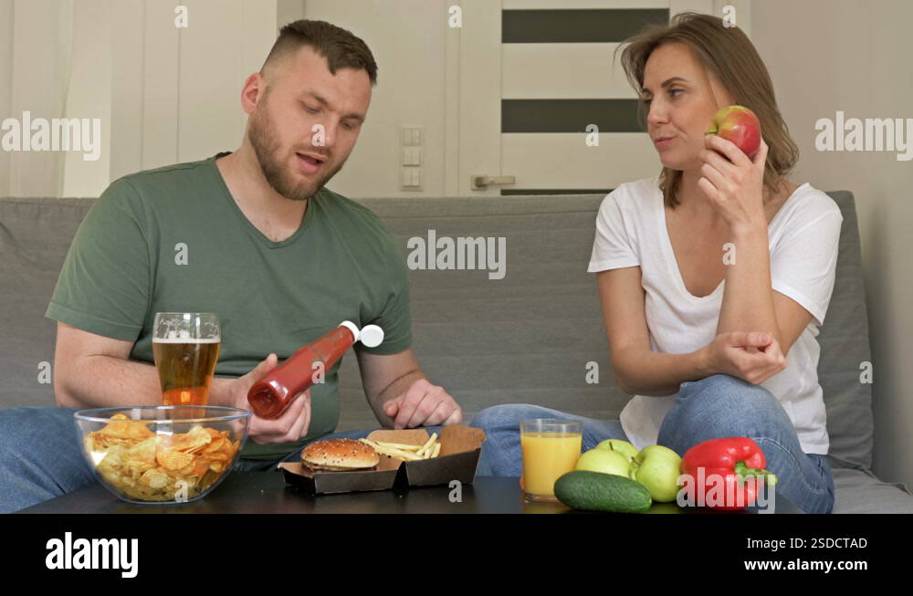 Healthy and unhealthy diet. Young couple has different eating habits ...