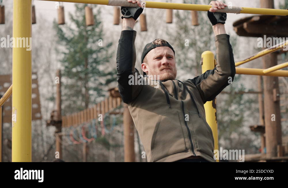 sportive fit male doing hand pull up exercise on sports playground ...