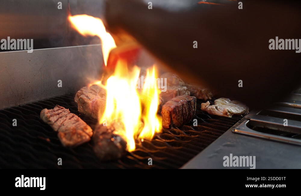 steak being flame grilled over a gas fire by a chef in a restaurant ...