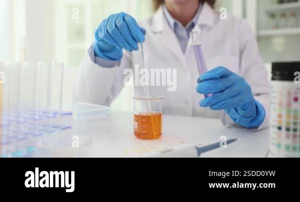 Female scientist conducts chemical research stirring liquid with glass ...