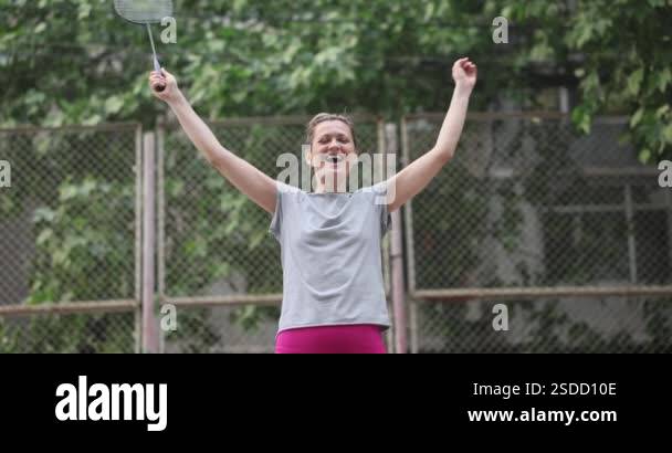 Female badminton player celebrates victory on urban court. Lady raises ...