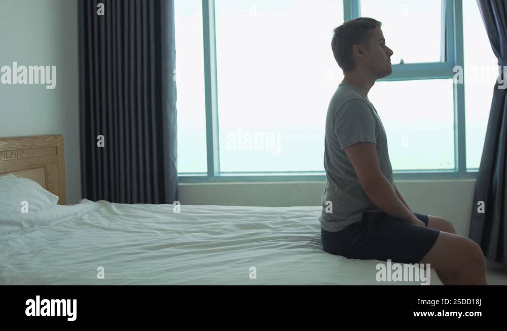 Young man falling on bed at home relaxing and smiling, slow motion ...