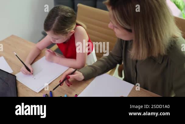Mother explains to daughter steps to solve simple math problem. Woman helps girl understand ...