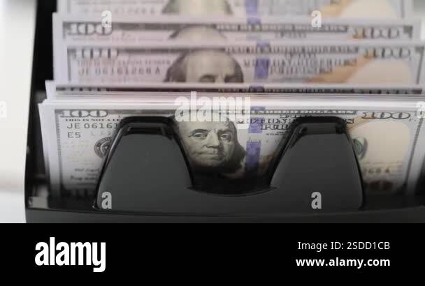 Money counting machine processes thick stack of dollar bills. Counting ...