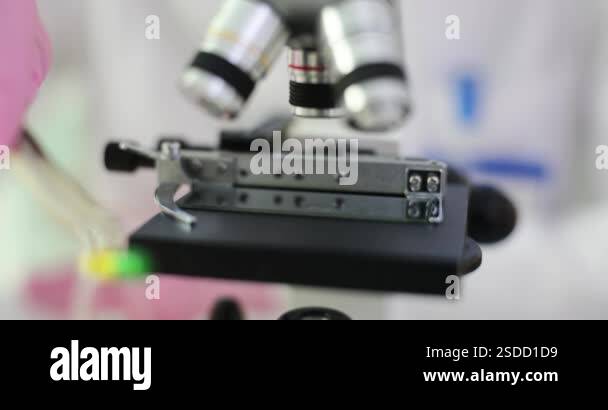 Scientist examines components of tablet using high-powered microscope ...