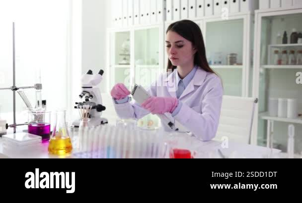Female scientist adjusts multichannel pipette preparing scientific experiment. Lab assistant ...