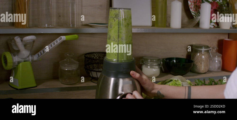 Fit female dancing in the kitchen while preparing green juice tox ...