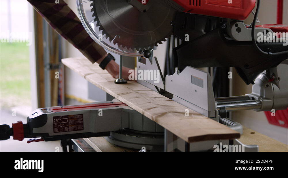 Handy man uses mitre saw to make a chop cut on a piece of wood - slow ...