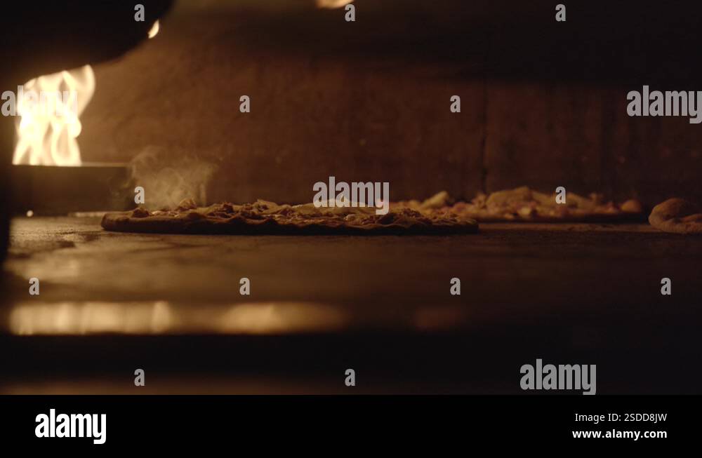 Slow motion shot Pizza in Wood fired Pizza Oven turning with pizza peel ...