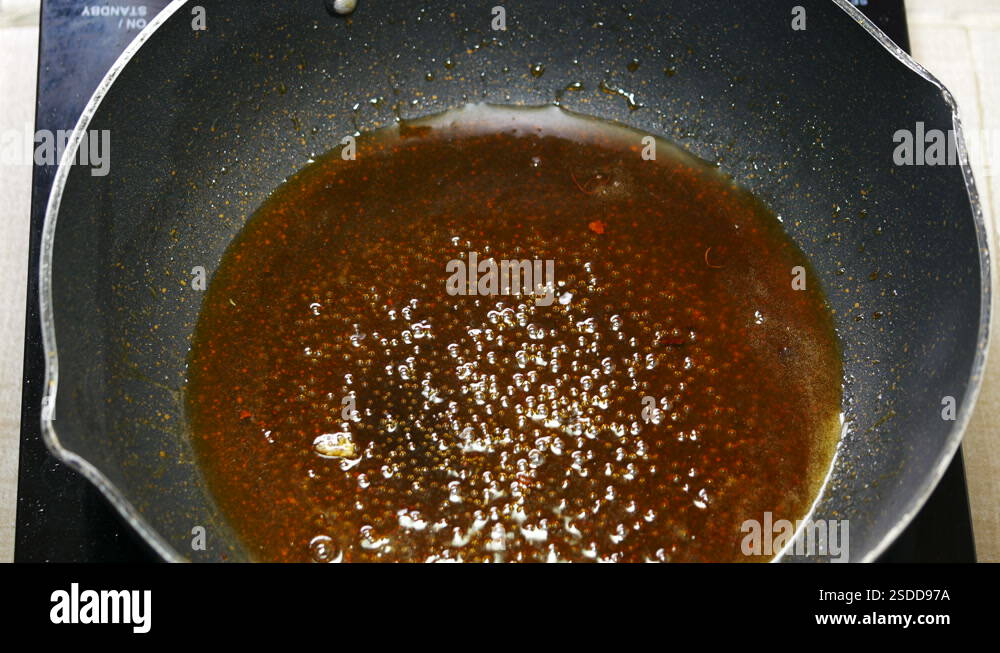 hand hold on wooden turner stir-fried tamarind sauce in induction pan ...