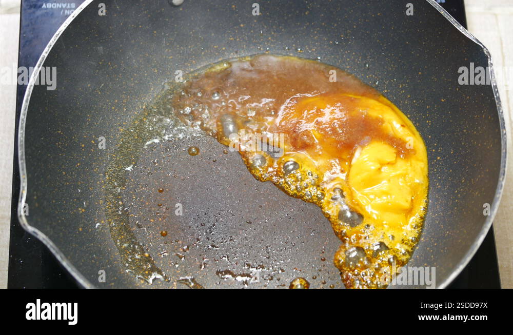 hand hold on wooden turner stir-fried tamarind sauce in induction pan ...