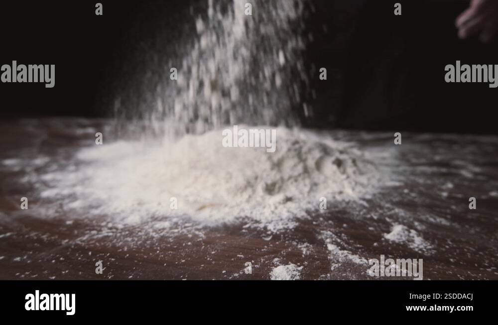 Flour is falling on the black table in slow motion. Someone throwing ...