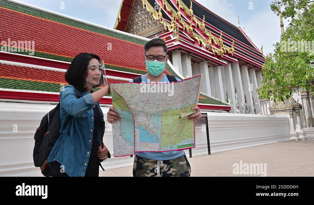 4K Asian couple in face mask and face shield exploring Wat Pho with map ...