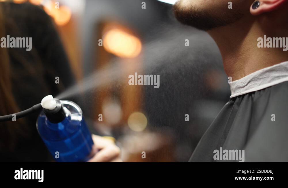Barber sprays parfume on client in barbershop after haircut and styling ...