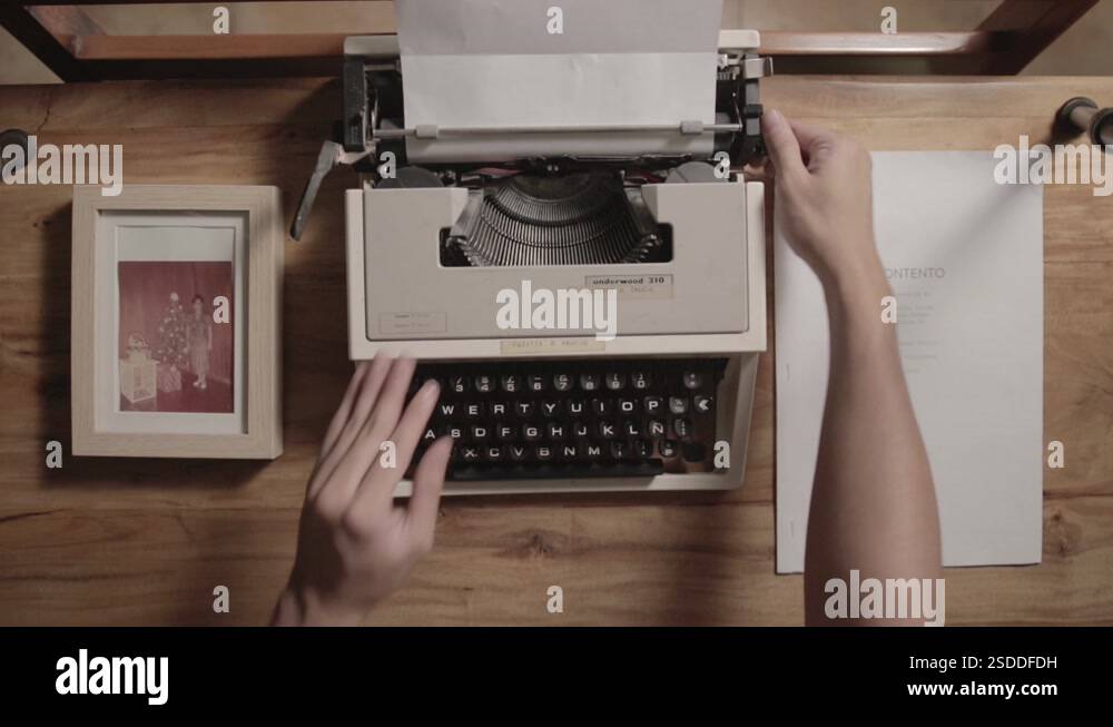 Hands of a book writer loading paper in an old typewriter and typing ...