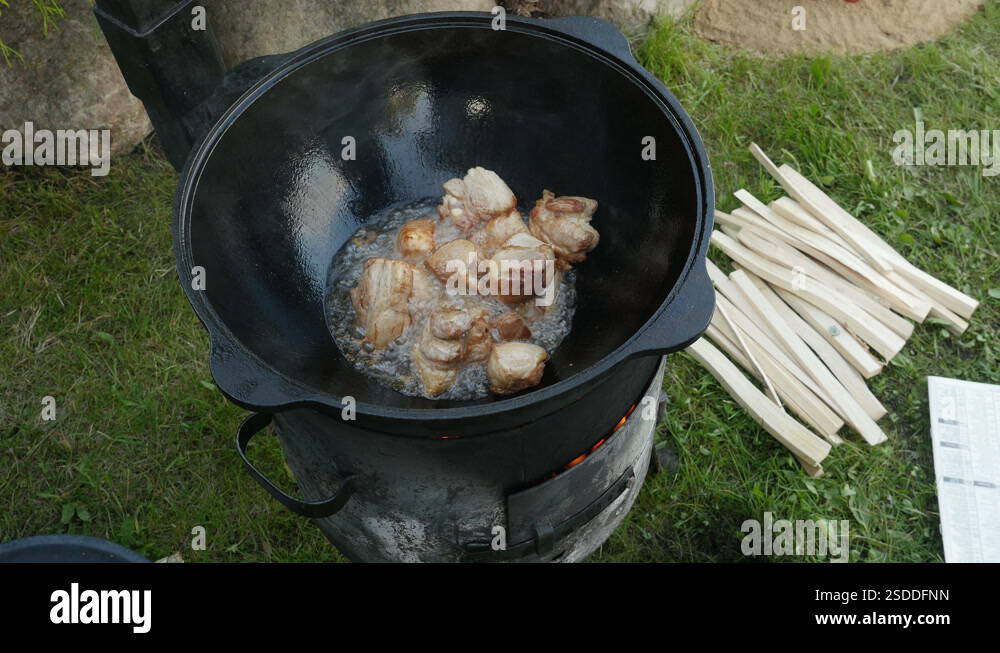 Cooking process, frying pork meat in large cauldron on open fire Stock ...