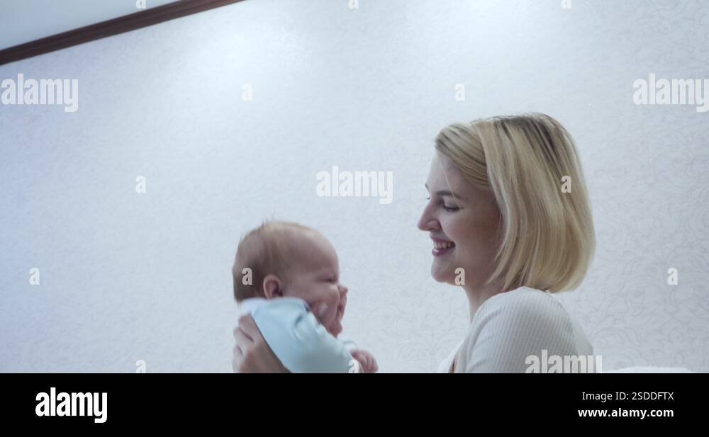 Mother carefully caresses her baby in her arms in the room Stock Video ...