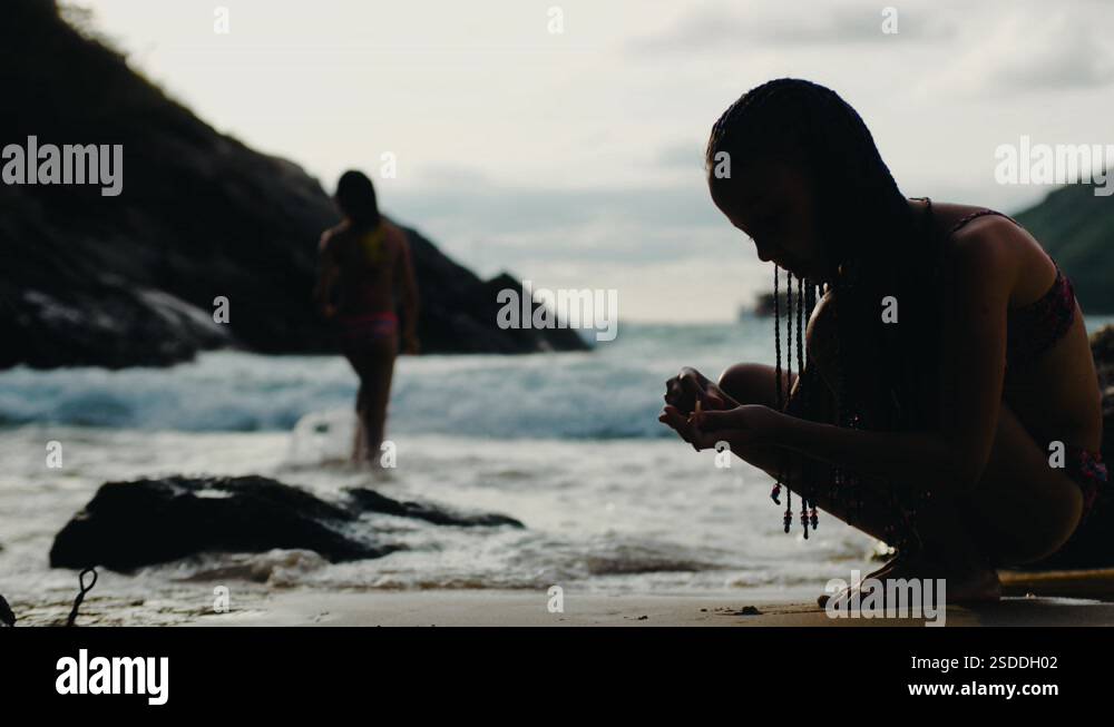 Children collect shells and rocks on the seashore during sunset on the ...