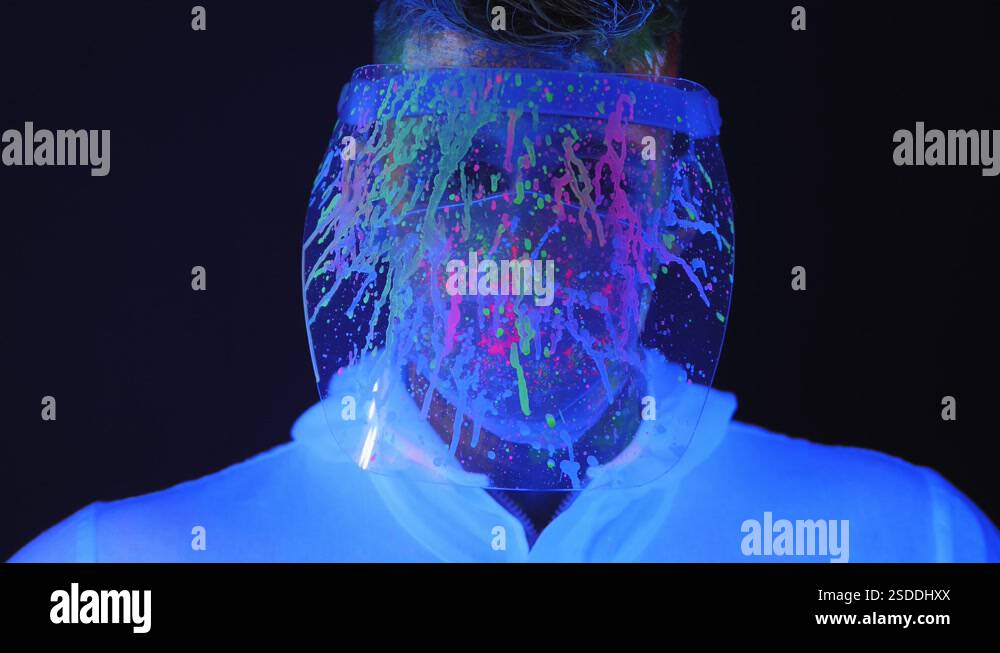 A male house painter in a white luminous suit and mask splattered with ...