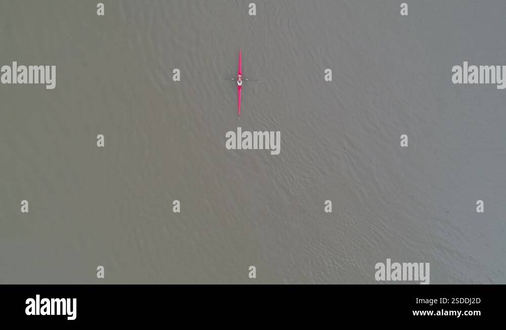 Birds eye view of rower in red canoe rowing from top to bottom of frame ...
