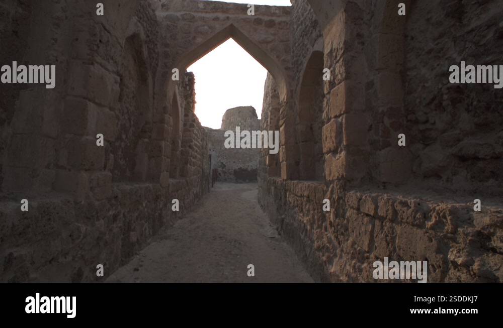 Sliding shot from an ancient ruin wall at the Bahrain Fort revealing ...