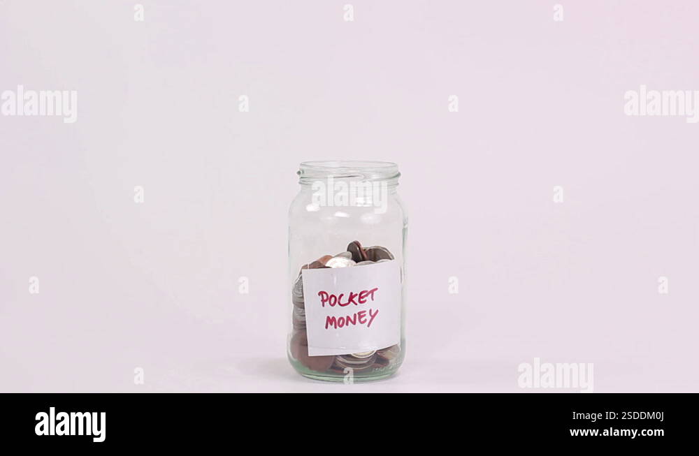 Savings Jar for Pocket Money. Dropping money and coins into the glass ...
