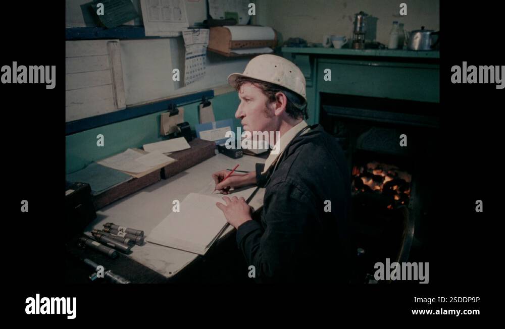 Miner is writing down data into a big notebook in office, Wales Big Pit ...