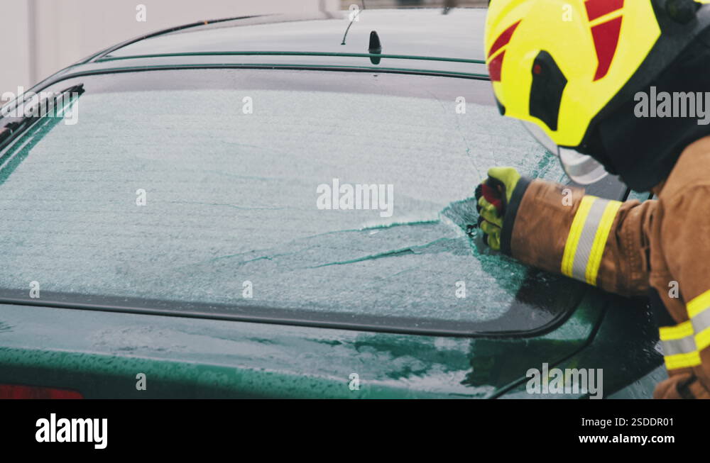 Car accident rescue, firefighter breaking the glass on the car. Close ...