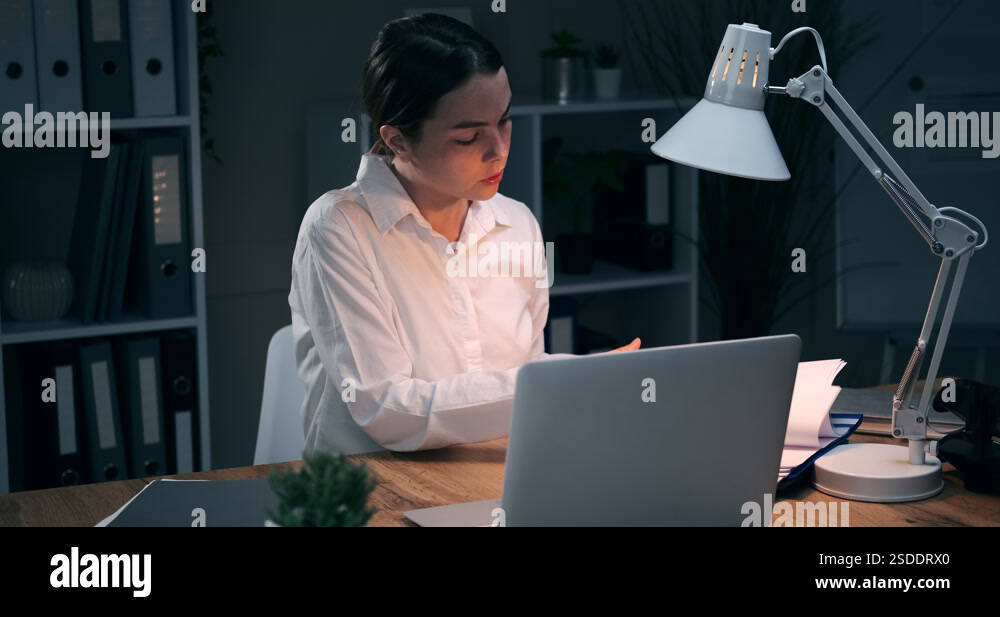 Businesswoman using laptop and doing paperwork at night office Stock ...