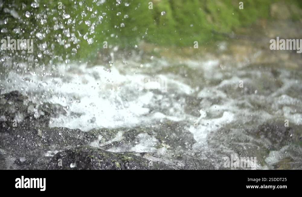 Waterfall drops of water on stone with a stream brook with green moss ...