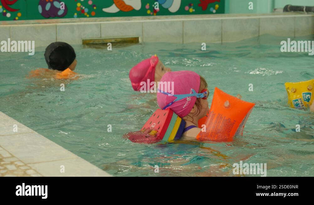 Group of kids has a swimming practice in the pool. Children learning to ...