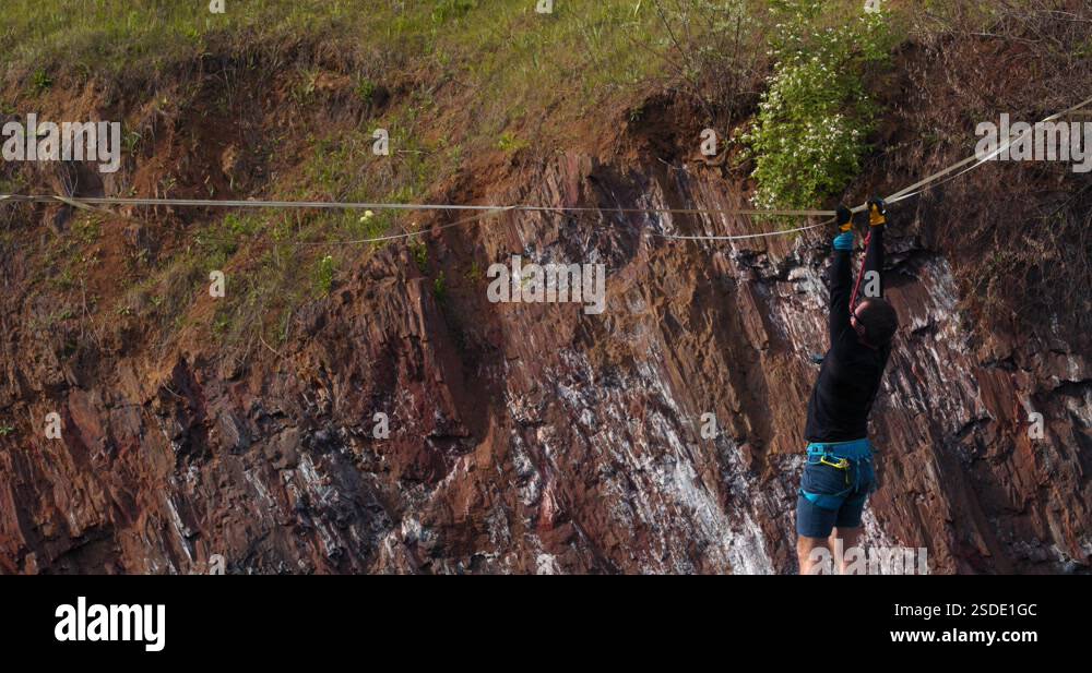 A man is hanging on a slackline with his hands, extreme sport, massive ...