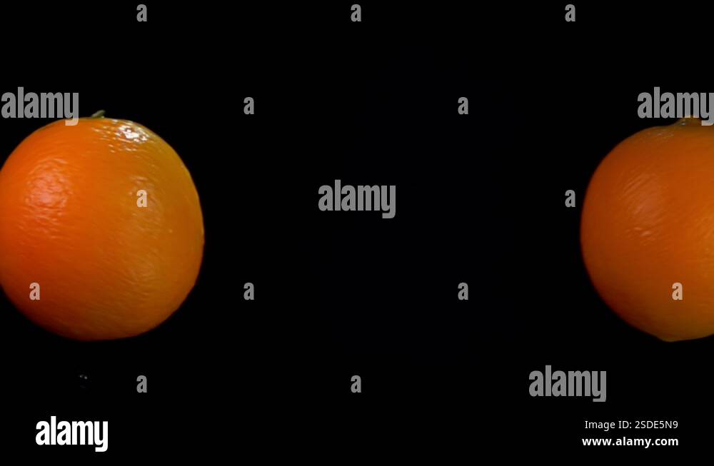 Two oranges are flying and colliding with each other rising splashes of ...