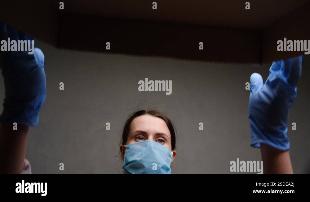 Shot from below of woman in medical face mask and latex gloves opened ...