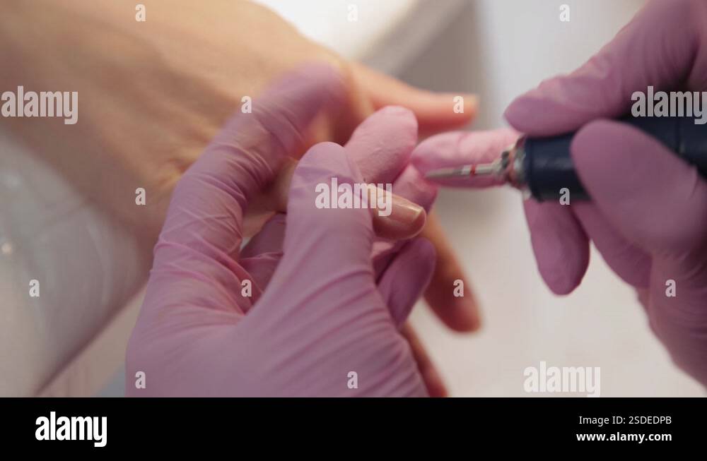 Manicurist cuts nails with a machine to a client in a manicure salon ...