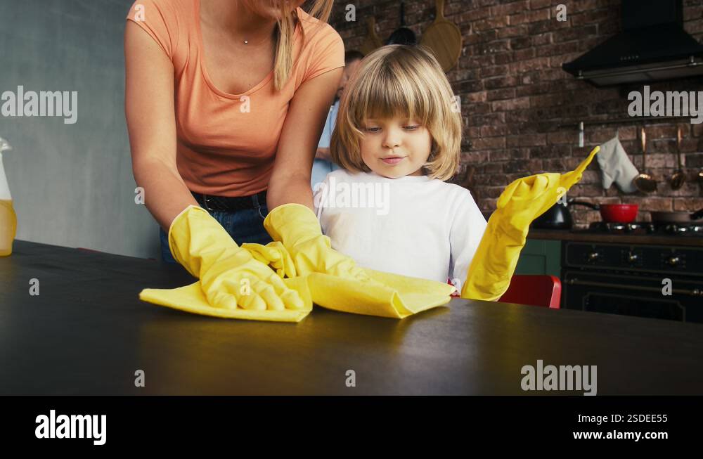 Mommy and son in yellow rubber gloves are smiling, talking, scrubbing ...
