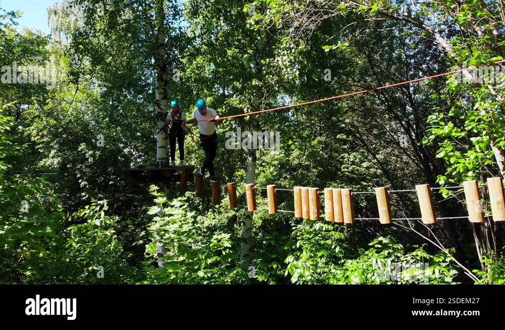 Extreme rope adventure in the park - man walking on the rope and stumps ...