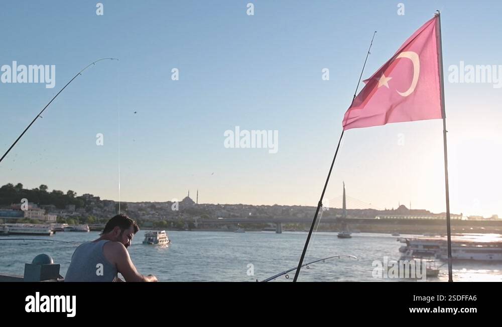 Turkish fisherman on the bridge. The Turkish flag flies in the wind ...
